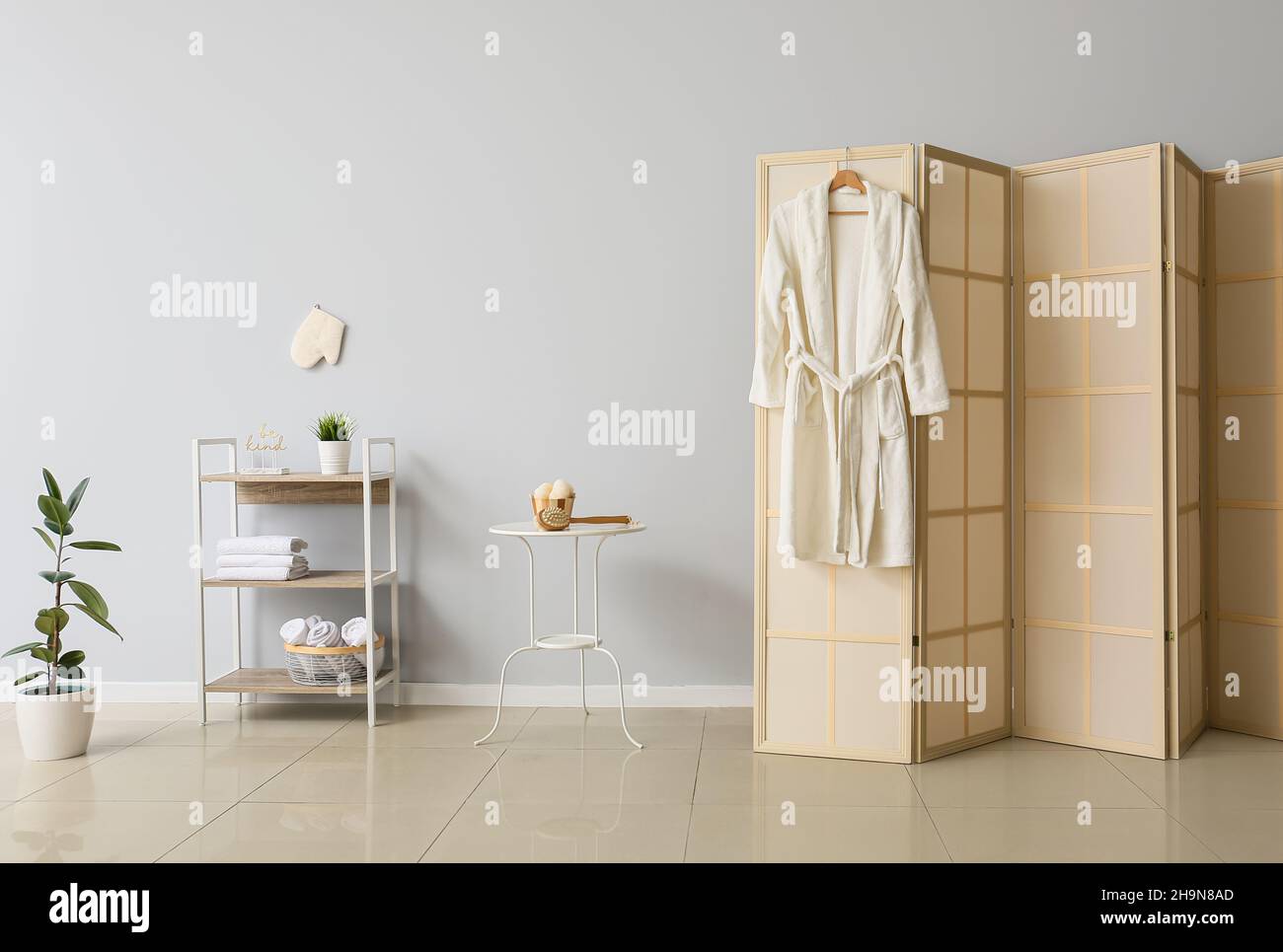 Folding screen with bathrobe and shelving unit in light room Stock ...