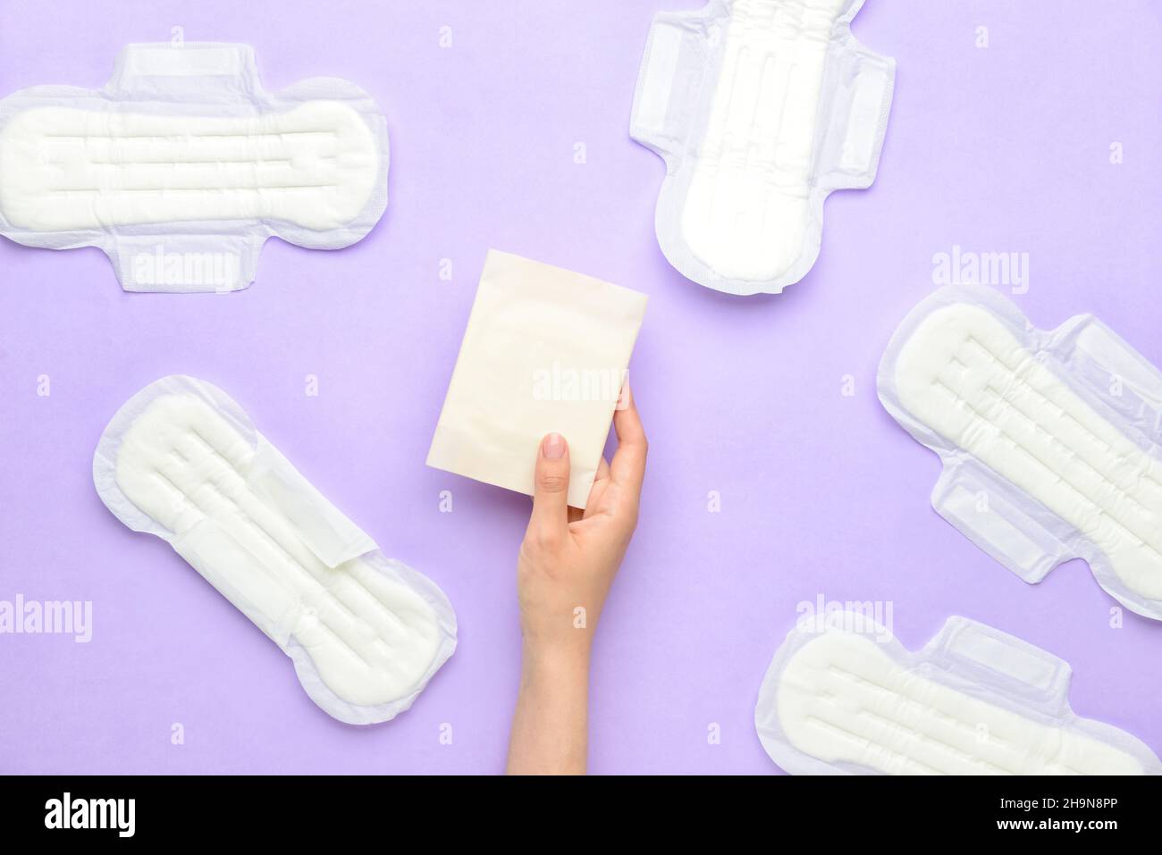 Female hand with menstrual pads on purple background Stock Photo - Alamy