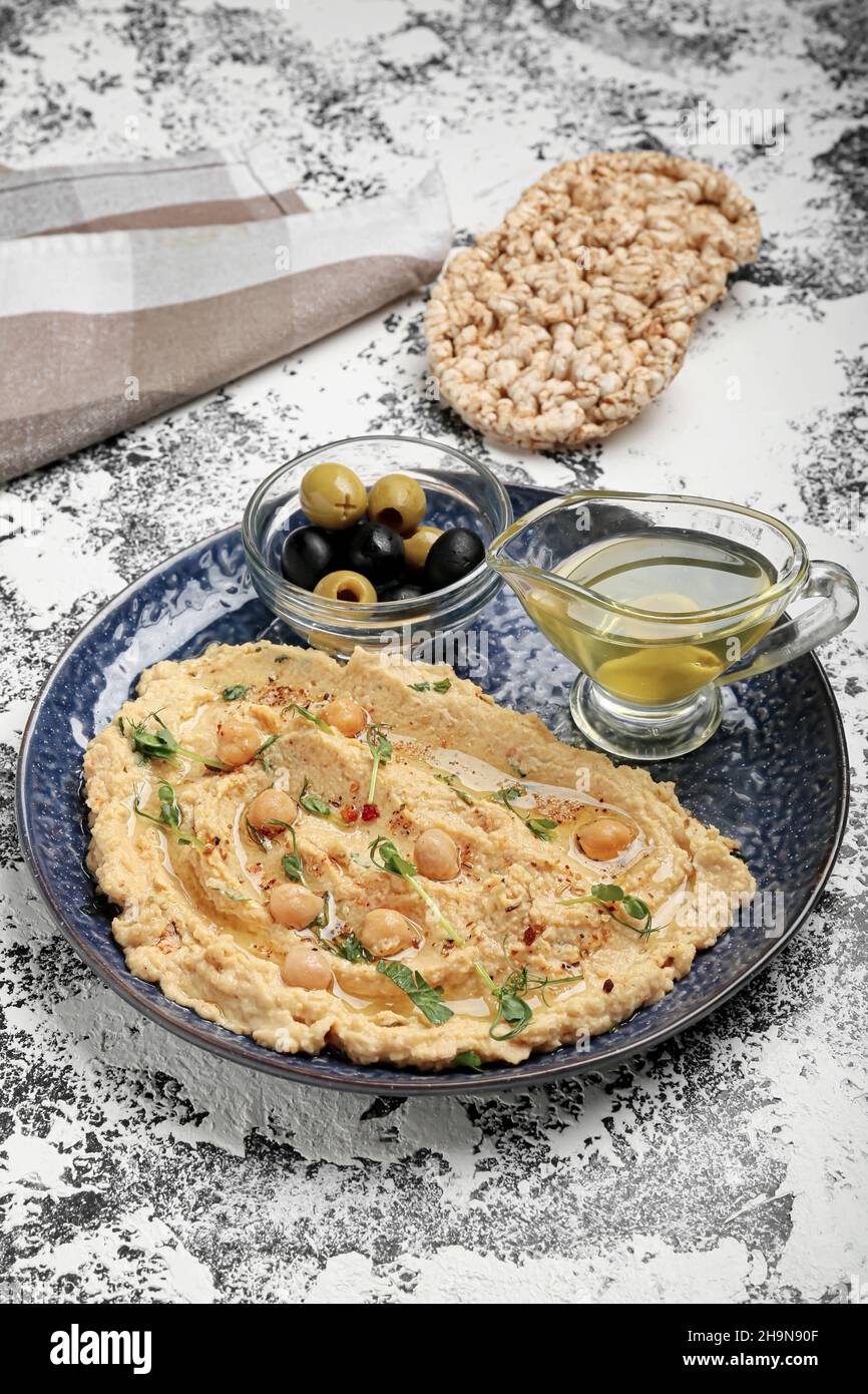 Plate with delicious hummus, olives and oil on color background Stock ...