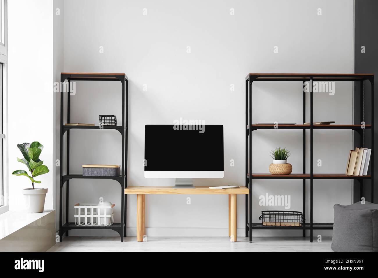 Interior of light room with table, computer screen and shelving units ...