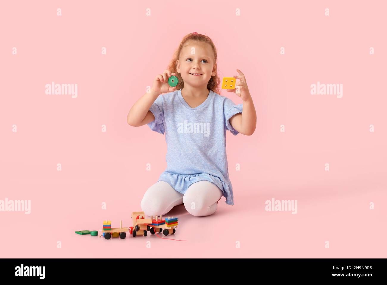 Cute little girl with building blocks on pink background Stock Photo ...