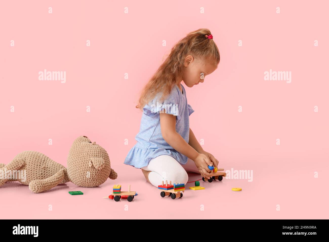 Cute little girl playing with building blocks on pink background Stock ...