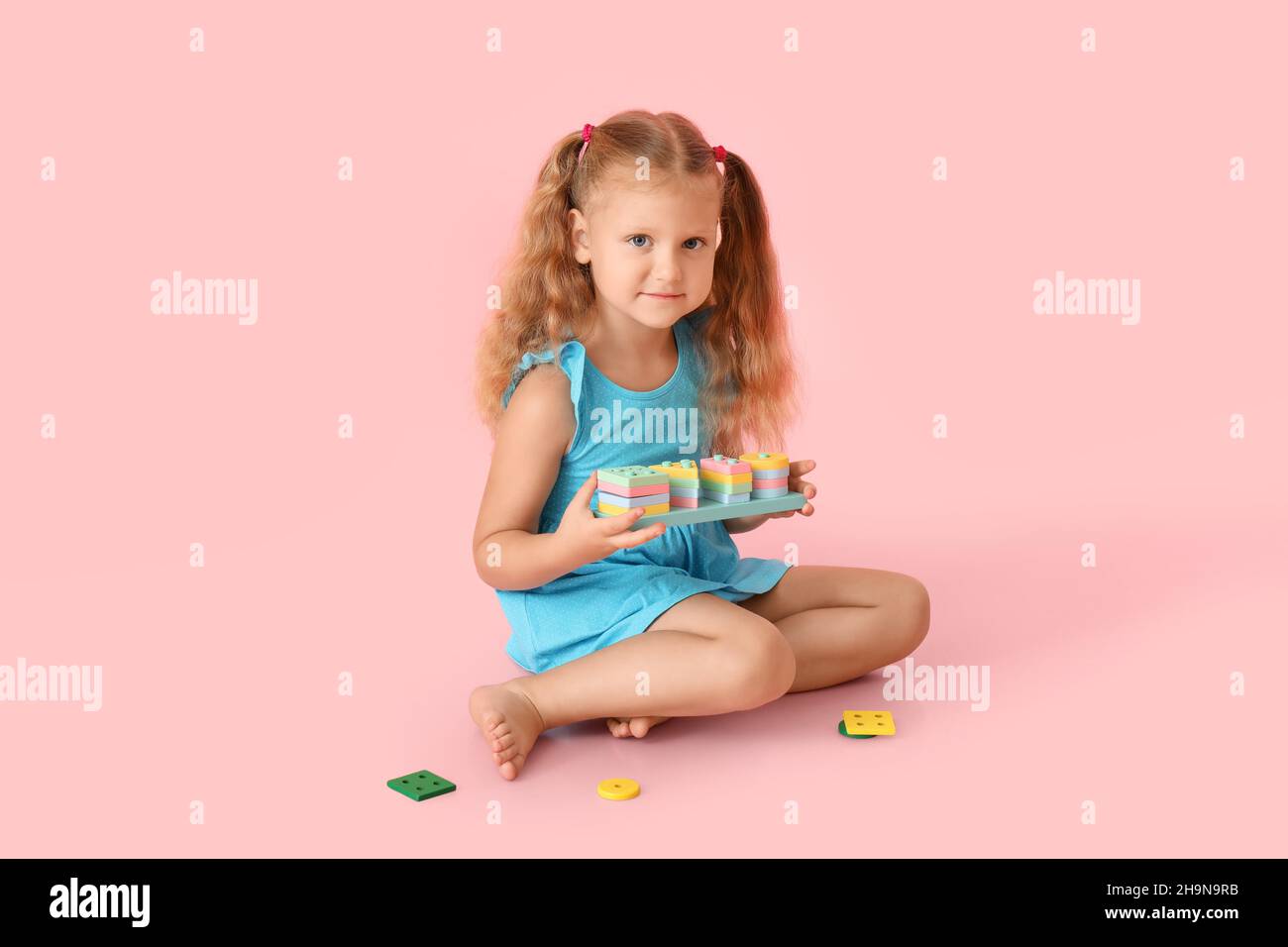 Cute little girl playing with building blocks on pink background Stock ...