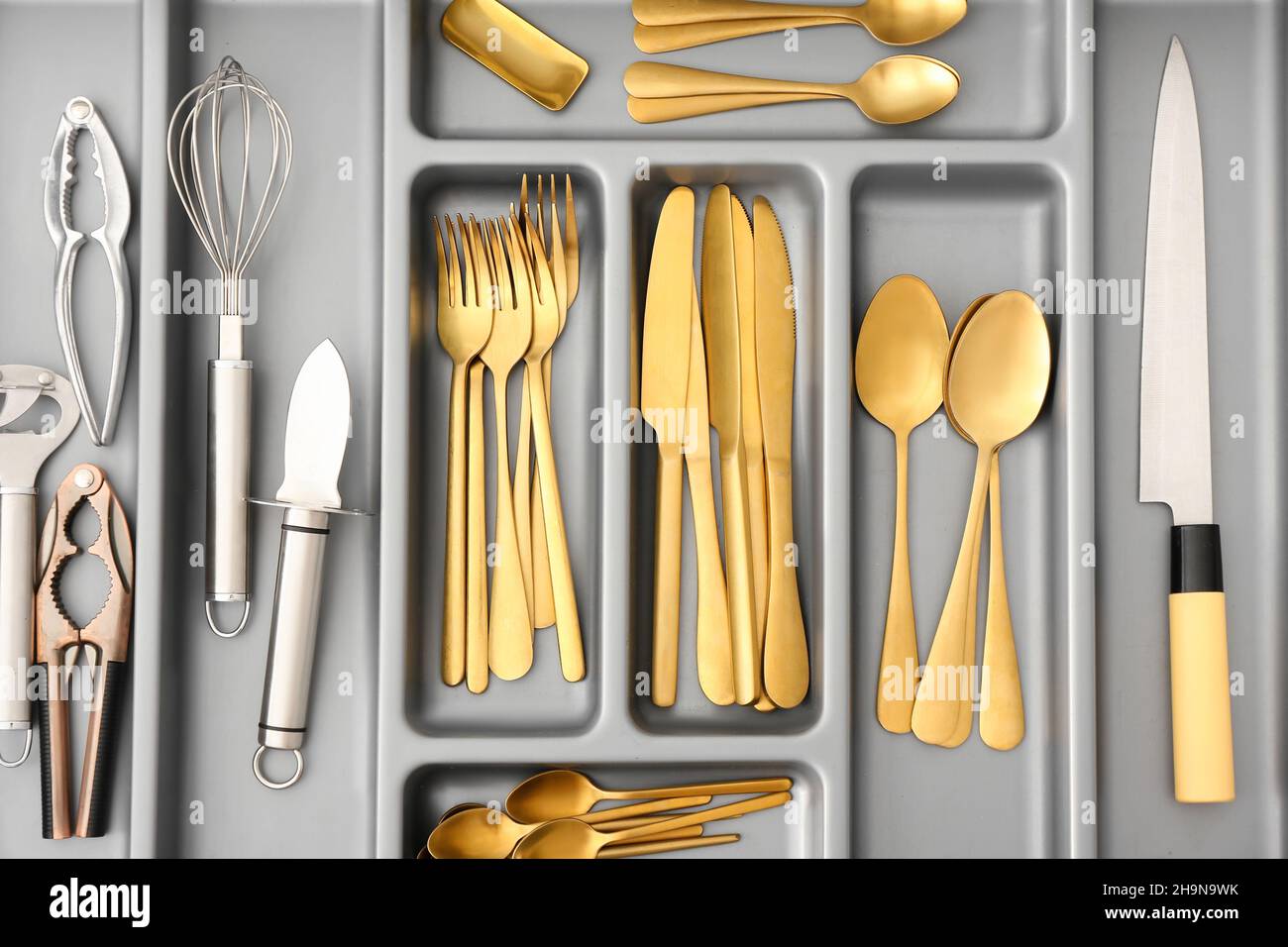 Open kitchen drawer with golden cutlery and utensils, closeup Stock ...