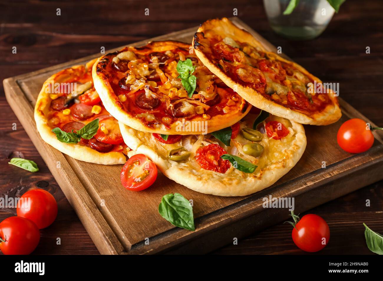 Board with delicious mini pizzas on wooden background Stock Photo - Alamy
