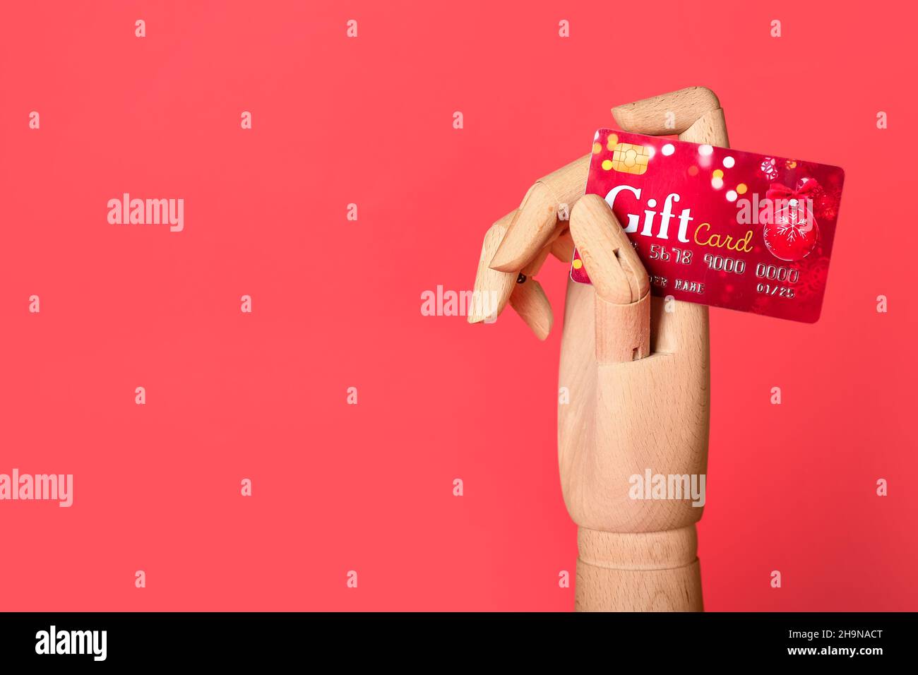 Wooden hand with gift card on red background Stock Photo - Alamy
