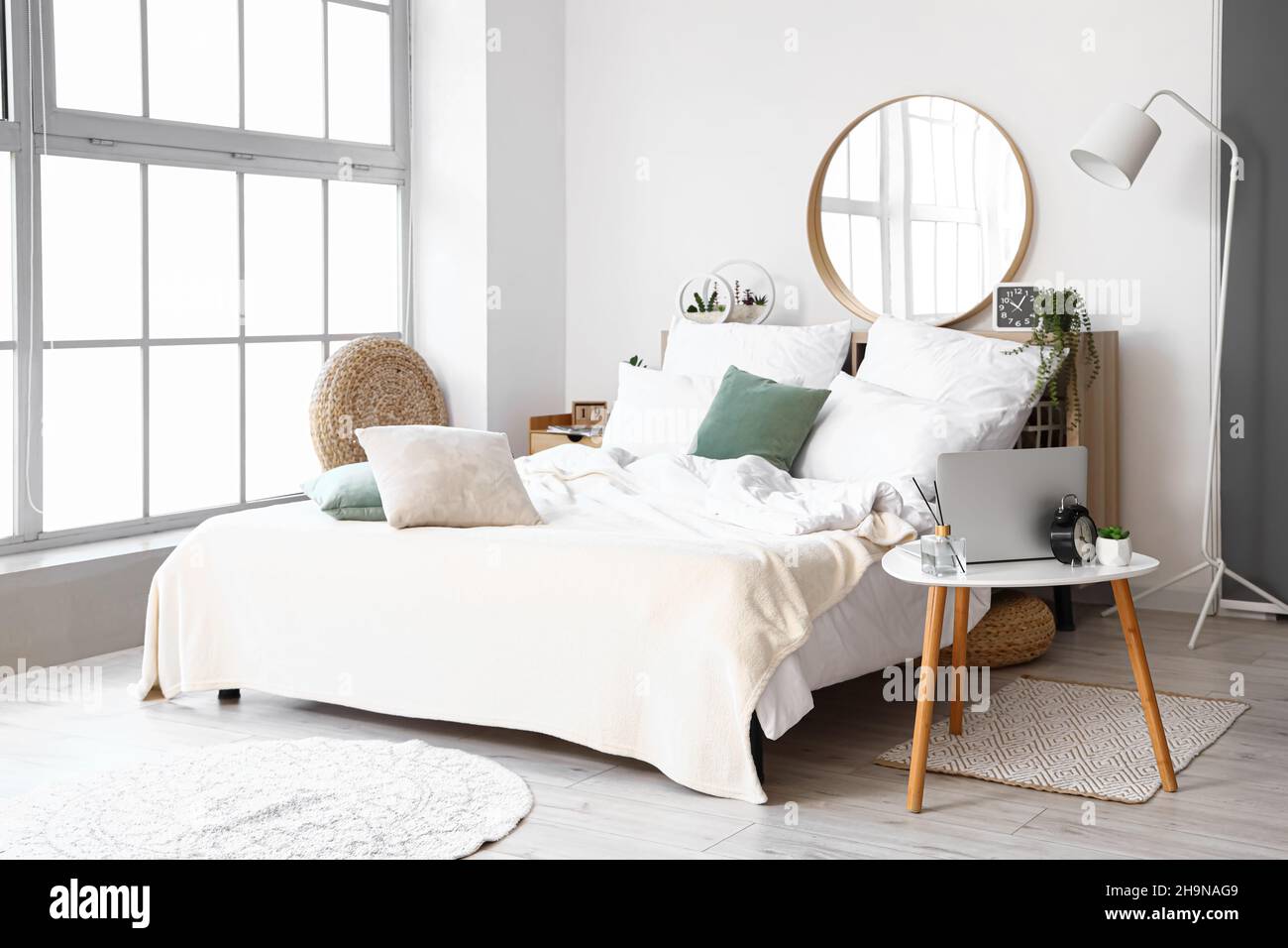 Stylish light bedroom with wooden bedside table near window Stock Photo ...
