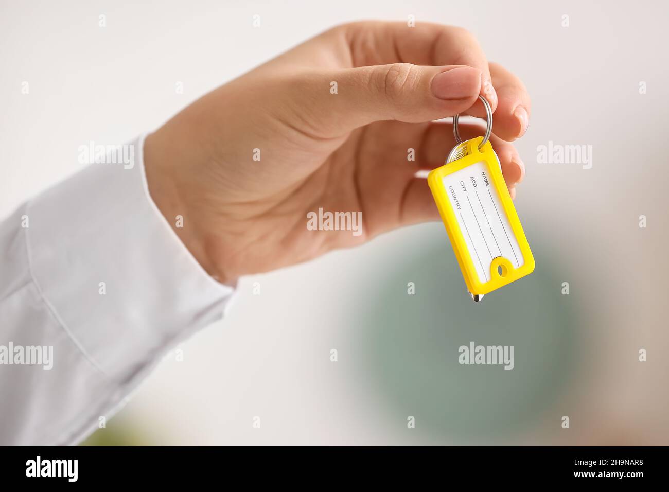 Female hand holding key on chain Stock Photo - Alamy