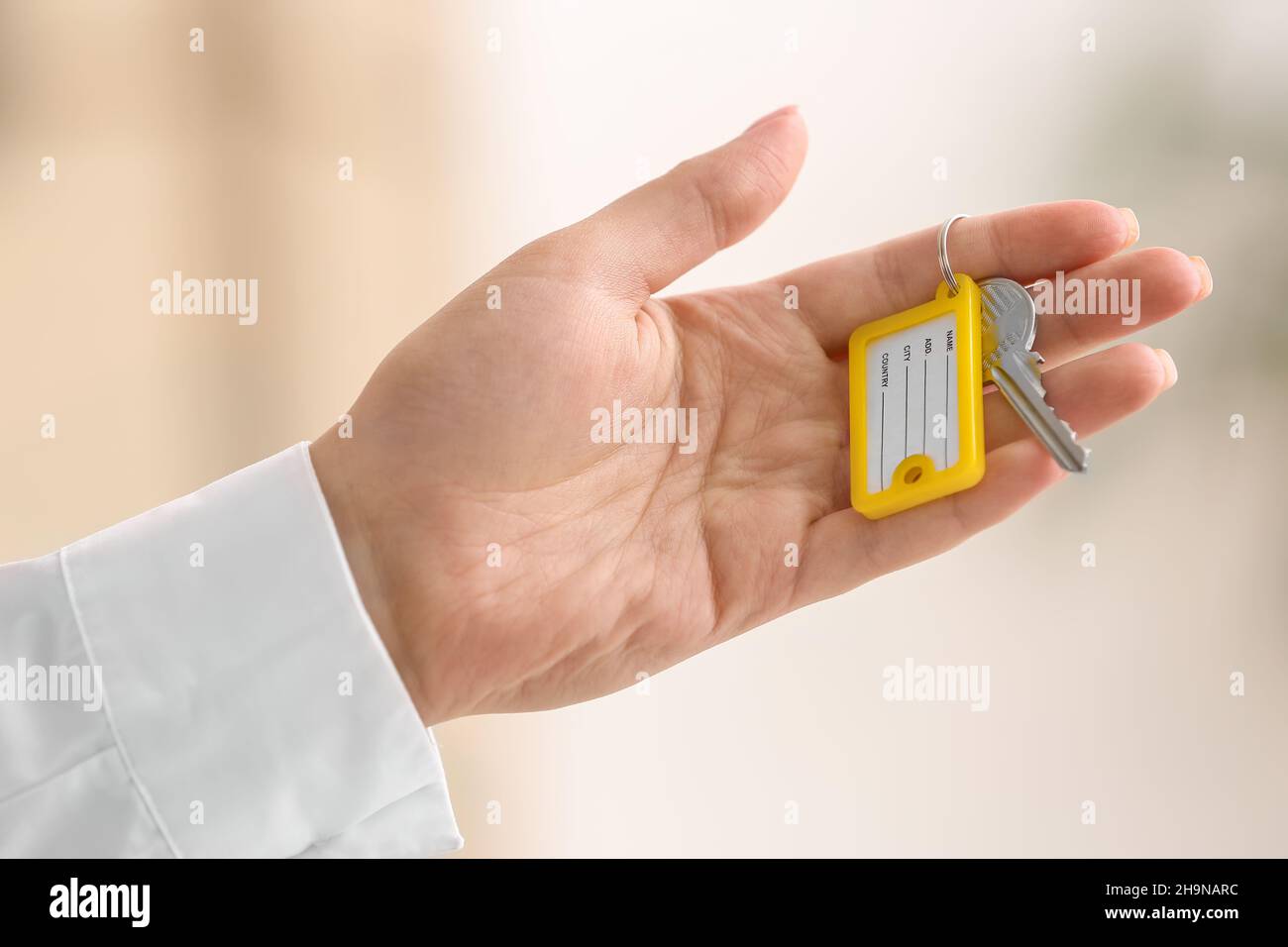 Female hand holding key on chain Stock Photo - Alamy