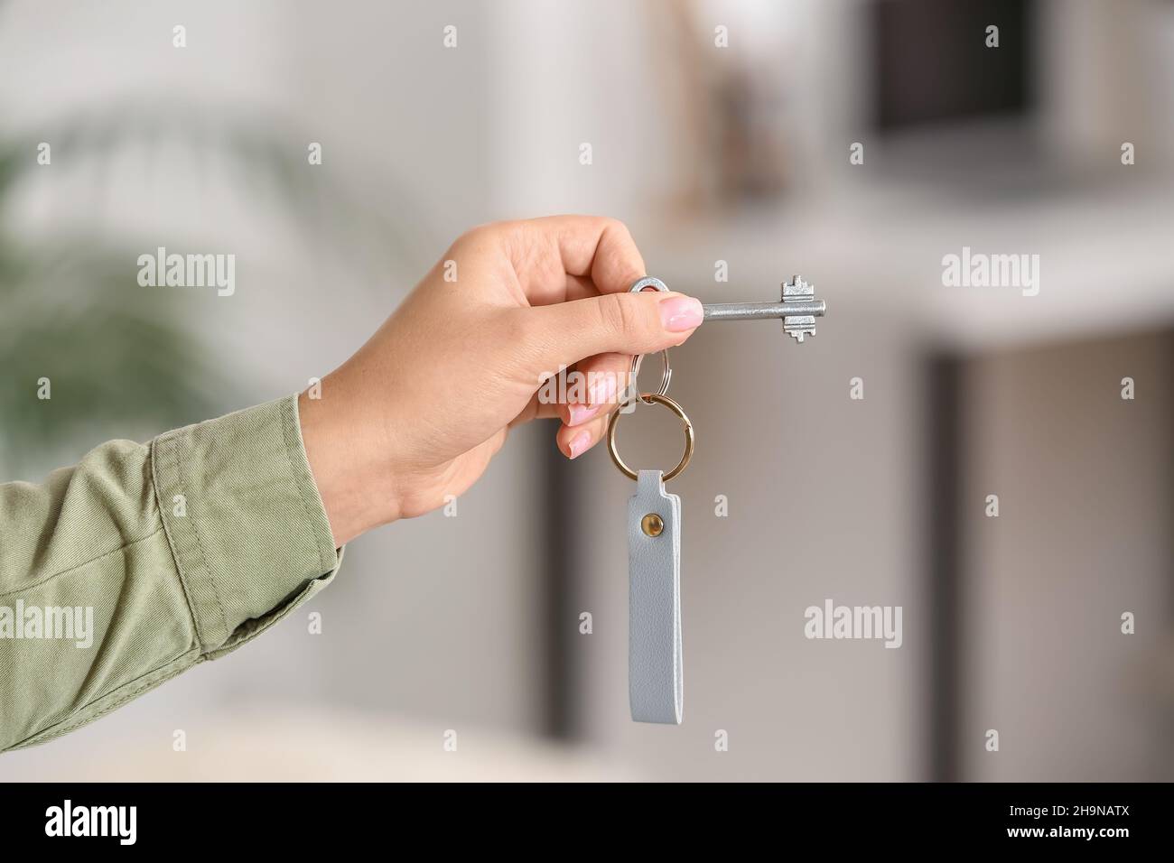 Female hand holding key on chain Stock Photo - Alamy