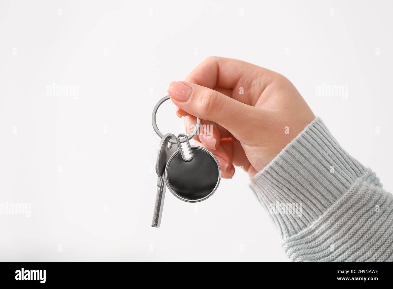 Female hand holding key on chain against light background Stock Photo ...