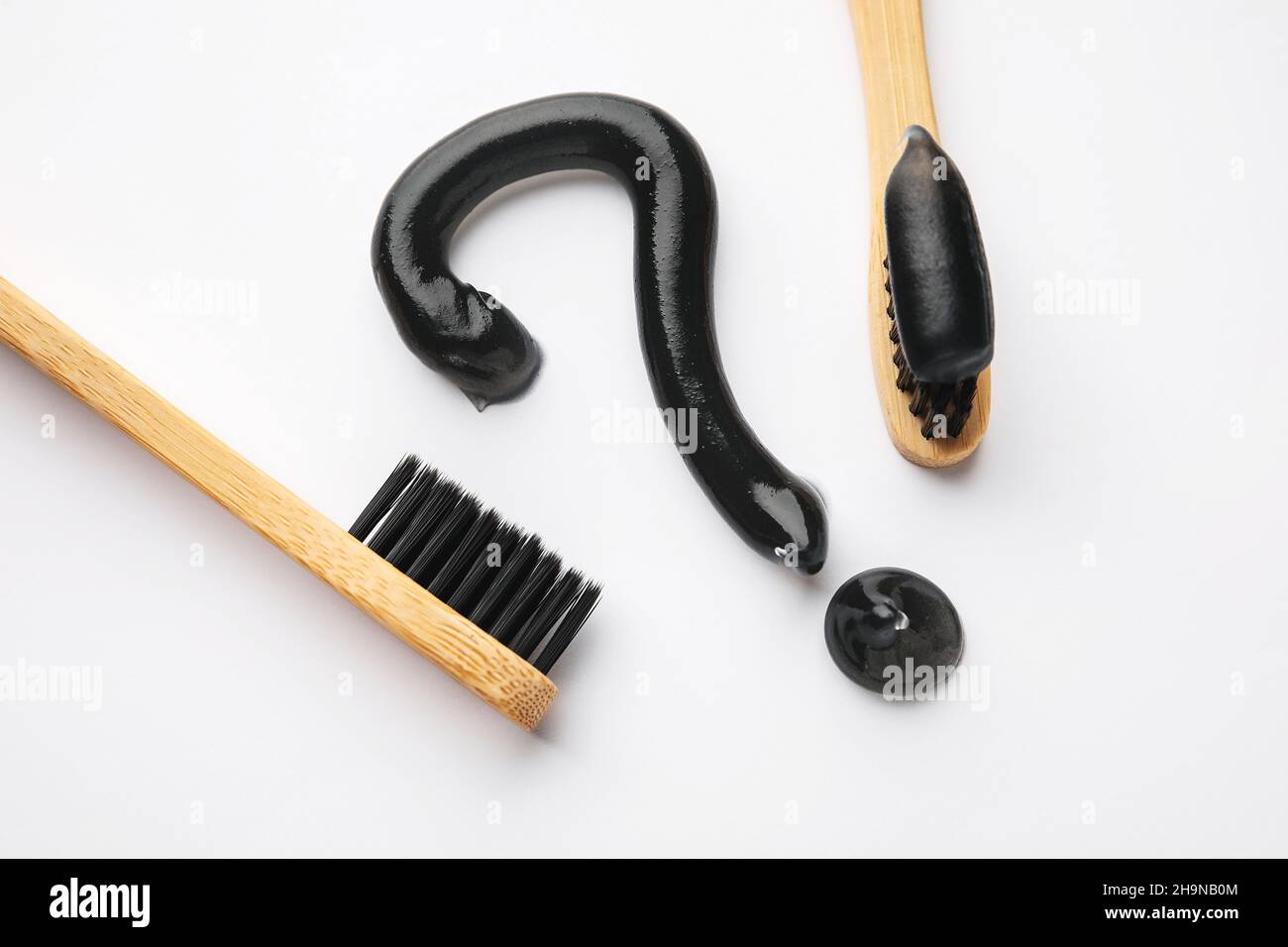 Question mark made of black tooth paste and bamboo brushes on white ...