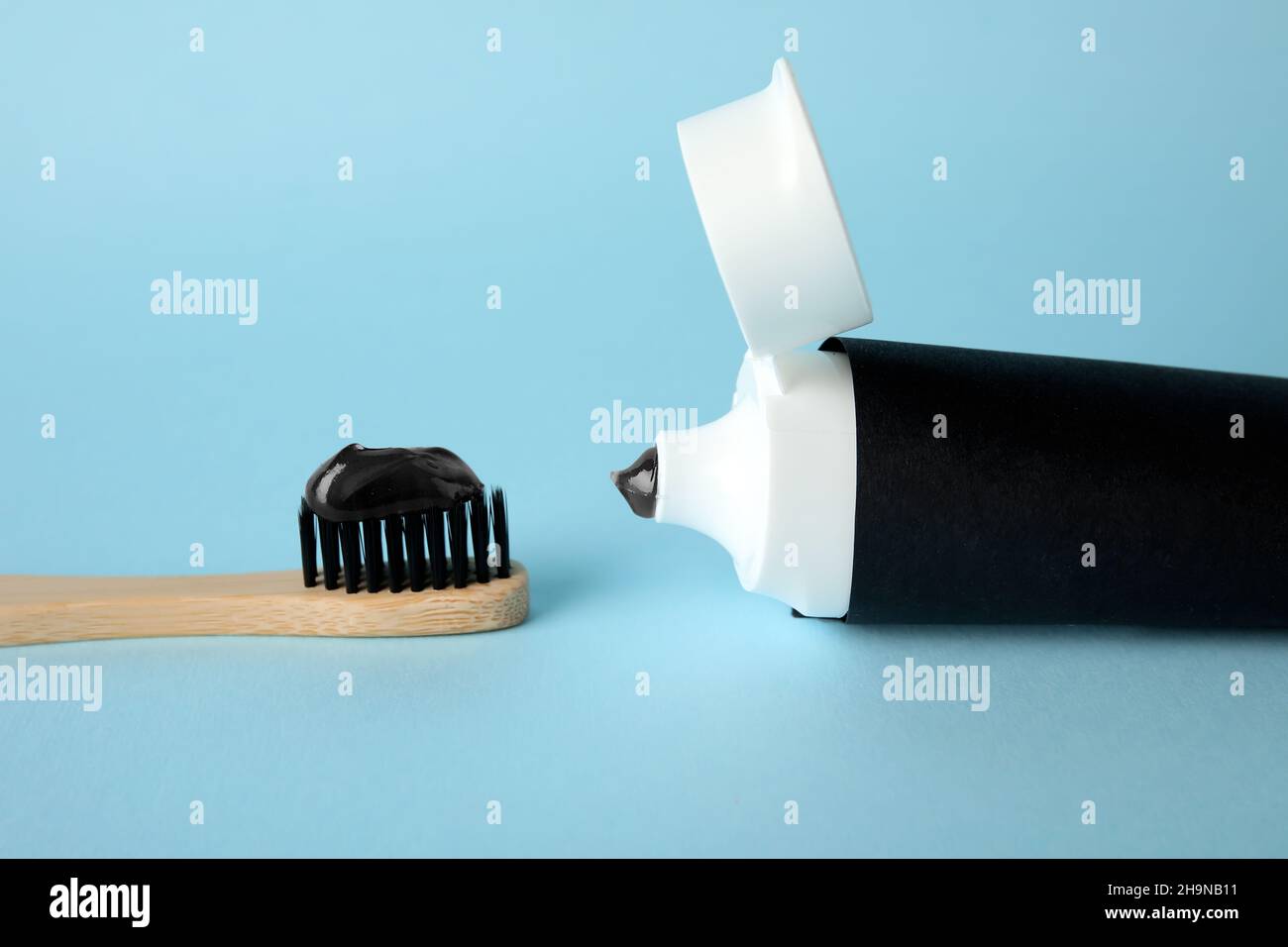 Bamboo brush with black tooth paste and tube on blue background Stock ...