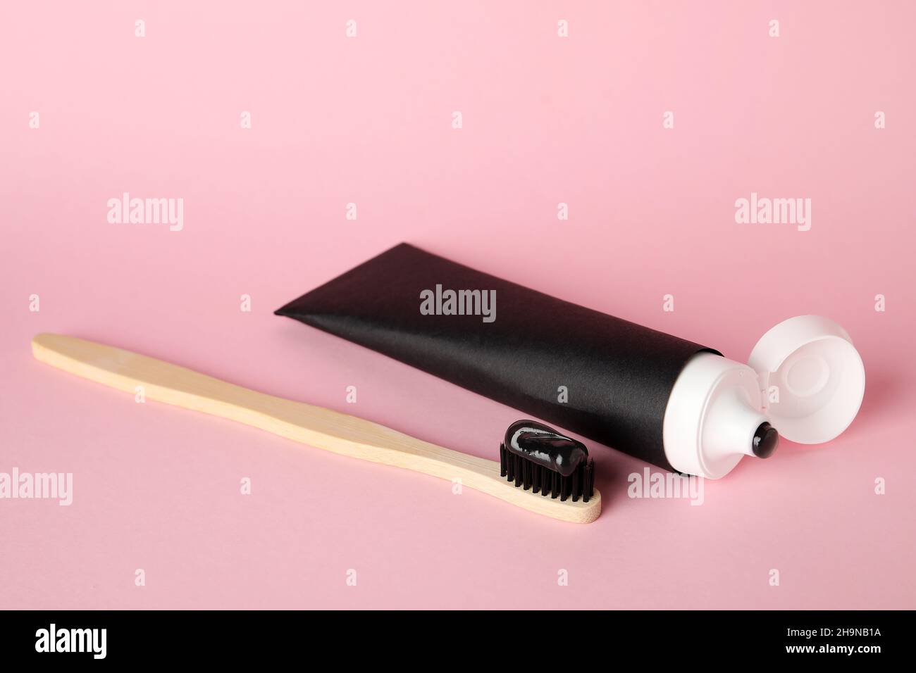 Tube of black tooth paste with brush on pink background Stock Photo - Alamy