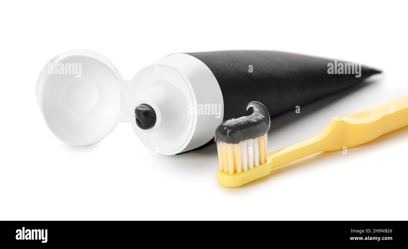 Tube with black tooth paste and yellow brush on white background Stock ...