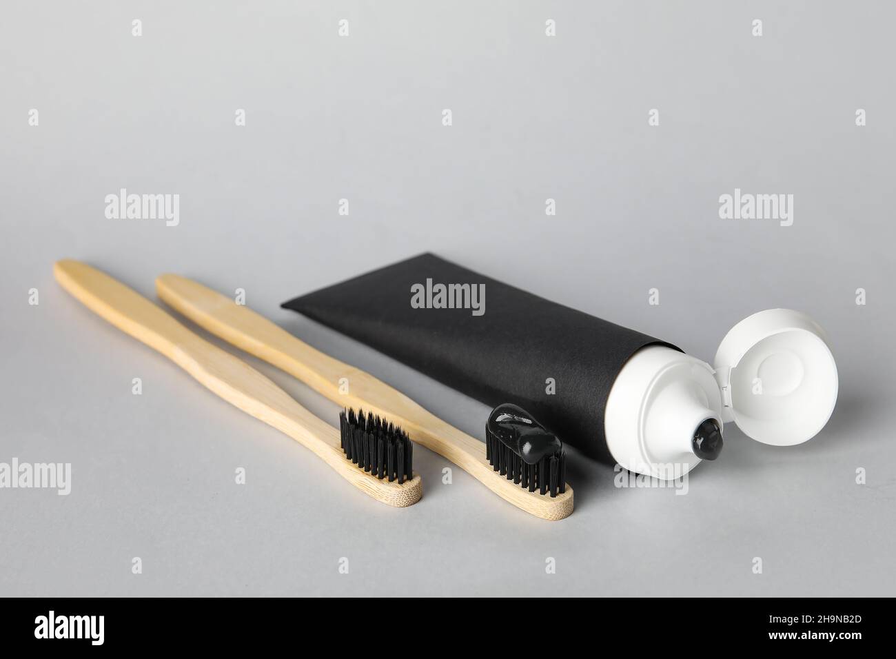 Tube with black tooth paste and bamboo brushes on grey background Stock ...
