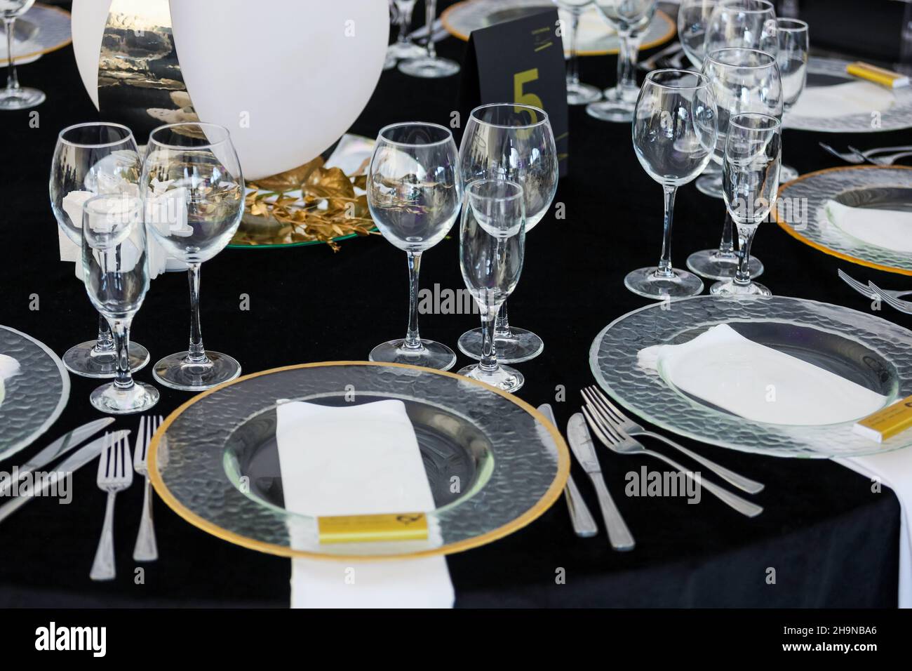 Restaurant interior, black tables with transparent plates and a golden ...
