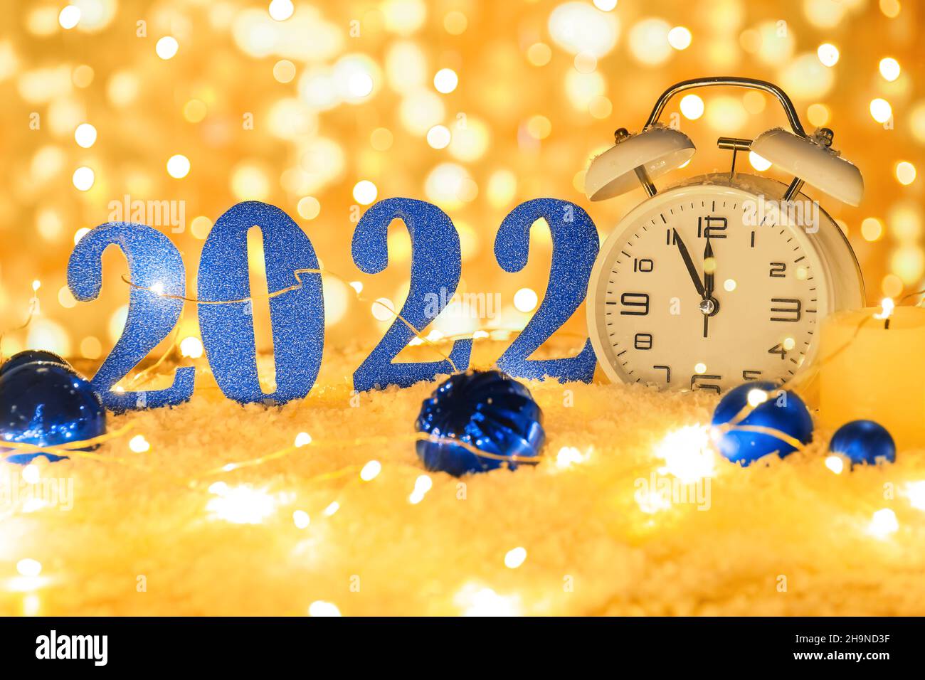 Stylish Christmas clock, decor, snow and figure 2022 on table against ...