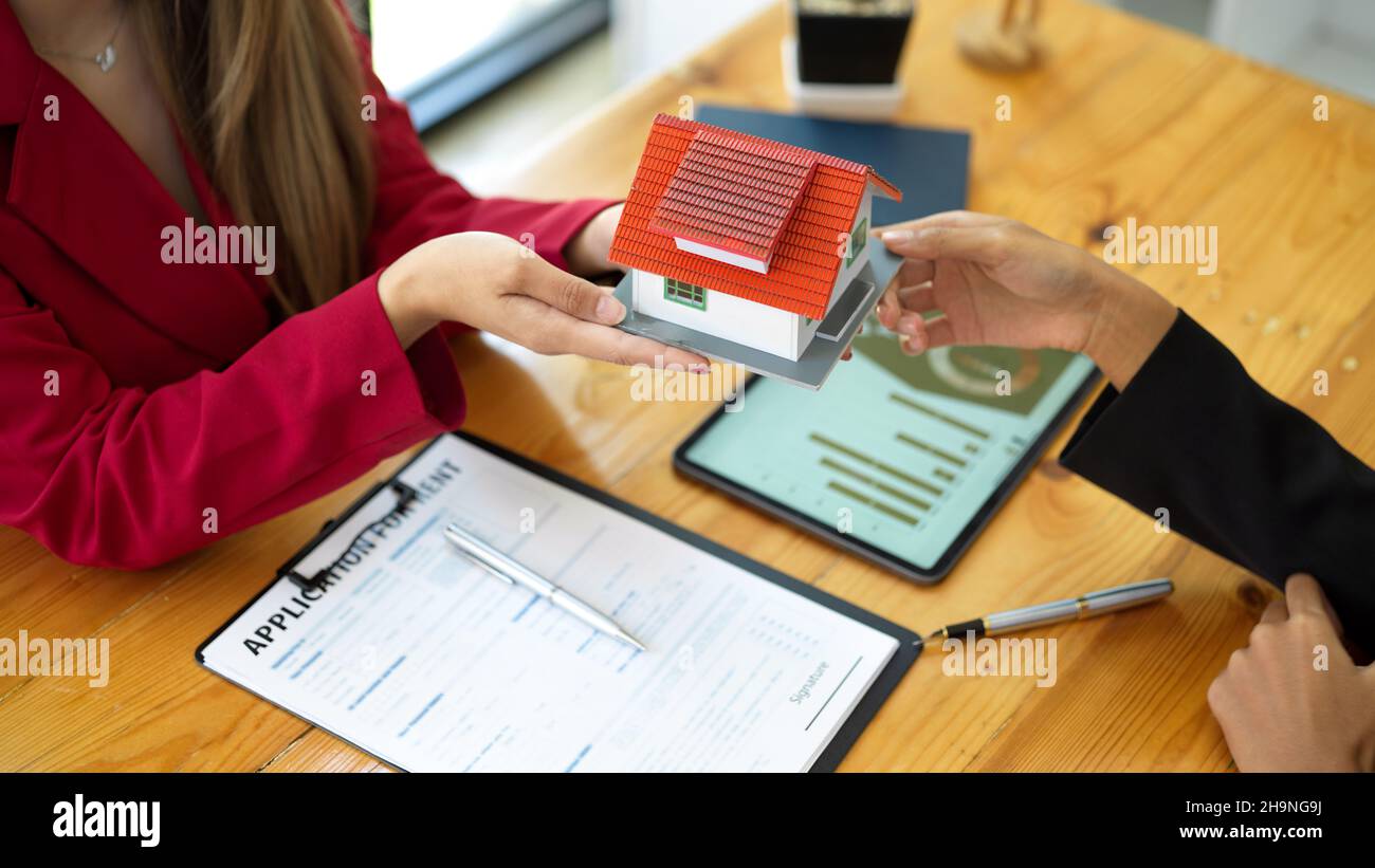 Close-up image female real estate broker holding house model with ...