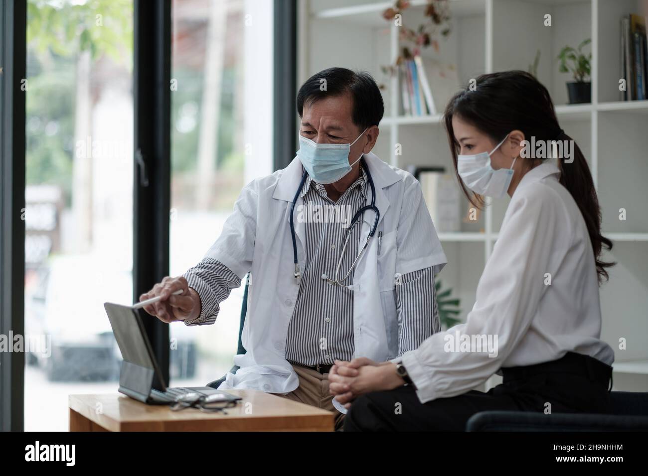 Senior asian doctor physician consulting young female patient, talking ...