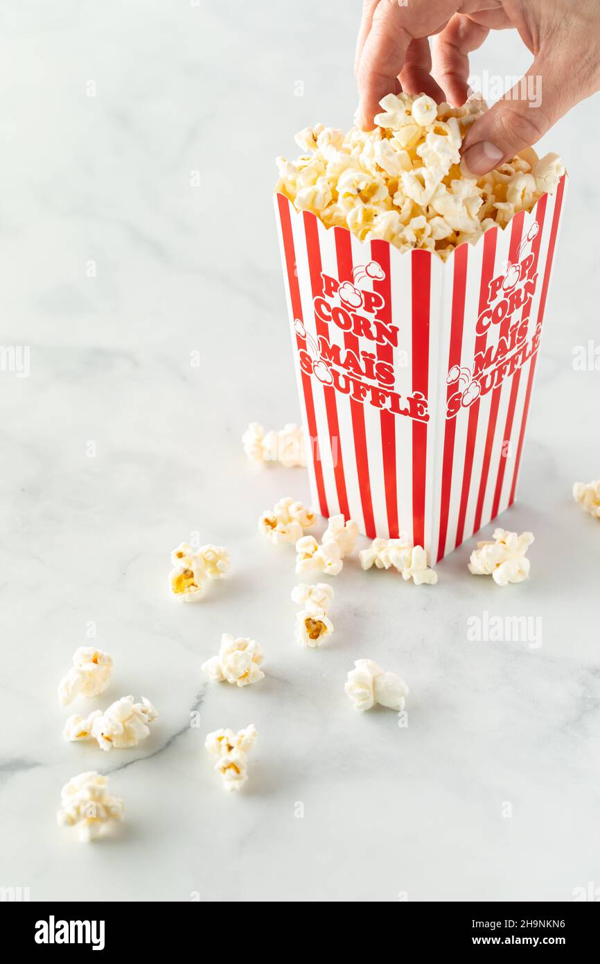 Someone taking a handful of popcorn from a popcorn carton Stock Photo ...