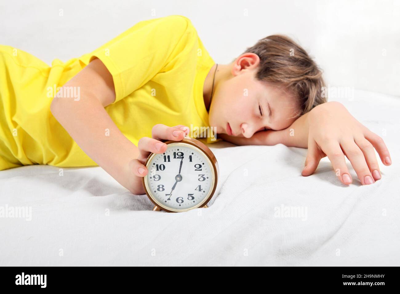 Kid sleep with Alarm Clock on the Bed Stock Photo - Alamy