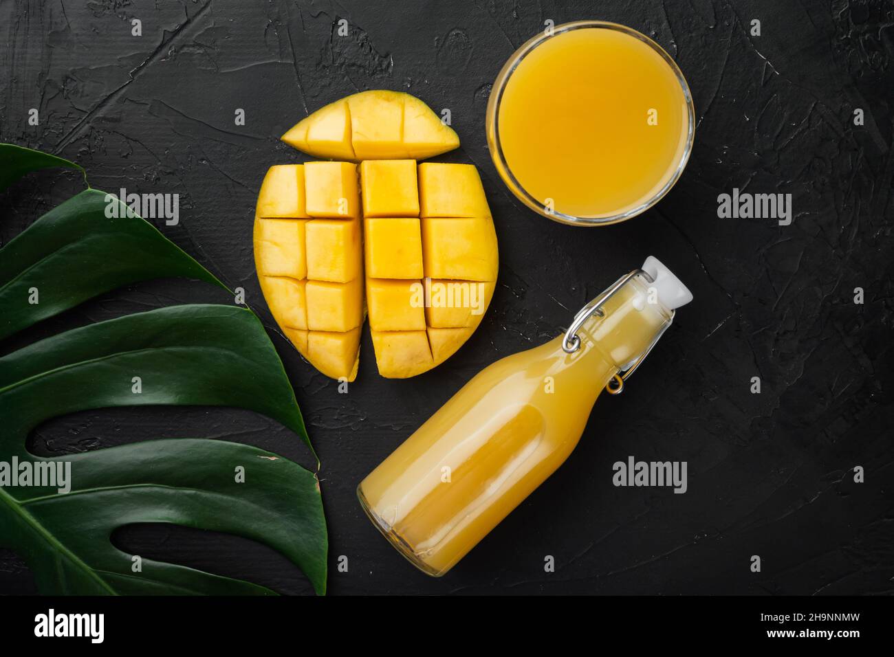 Glass bottle of mango juice set, on black dark stone table background ...