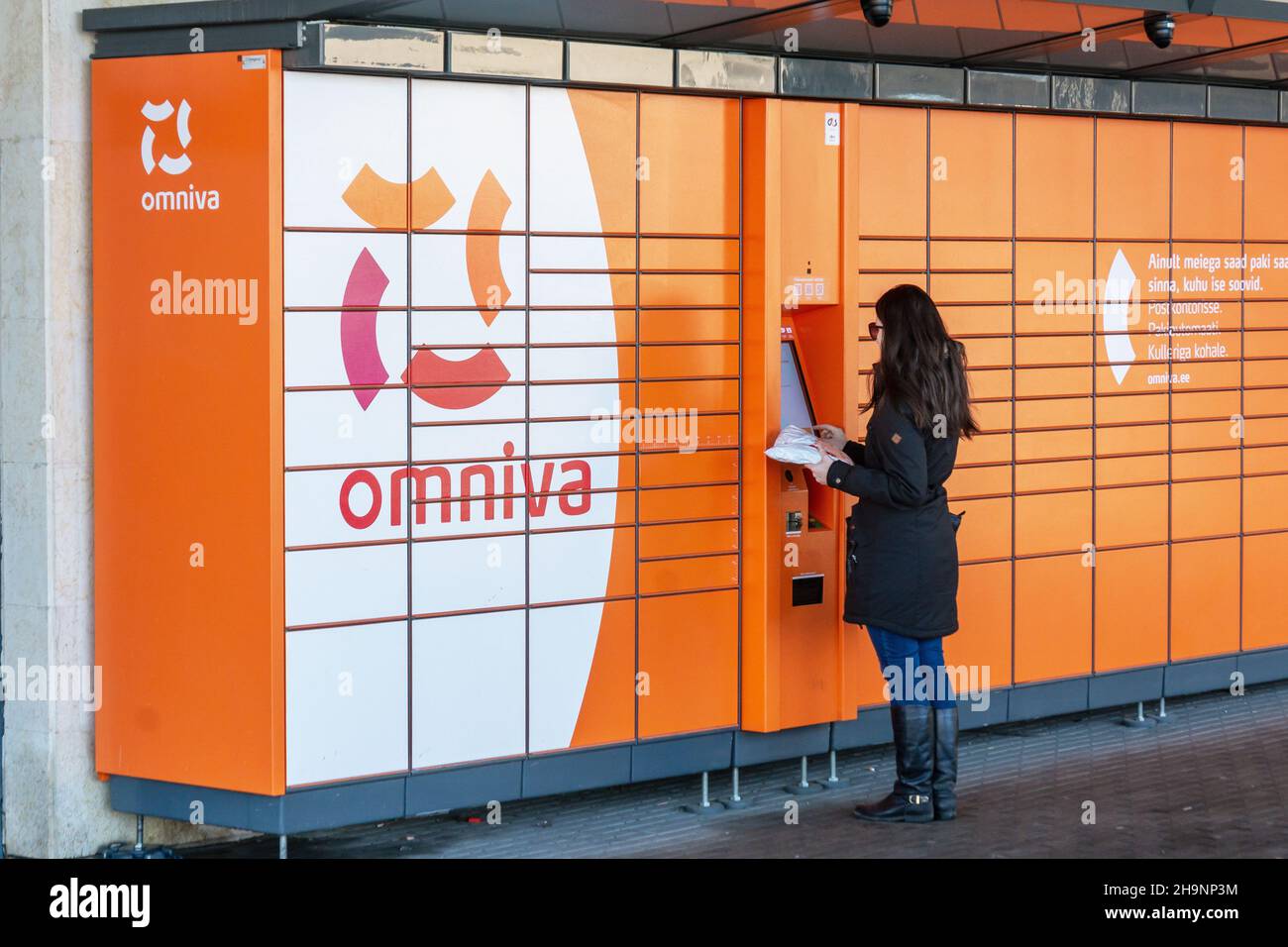 Woman using Omniva parcel locker at Balti jaam railway station in ...