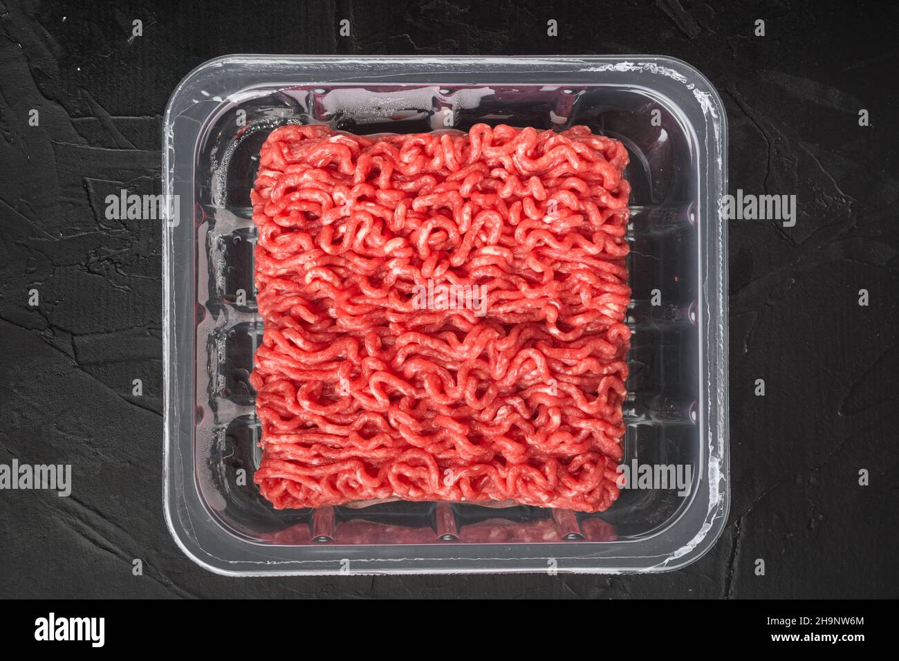 Raw Minced Meat in a transparent Plastic Container set, on black stone ...