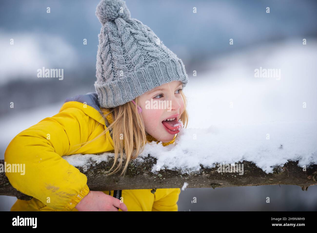 Winter girl eating snow outdoor. Funny christmas kids lick snow with ...