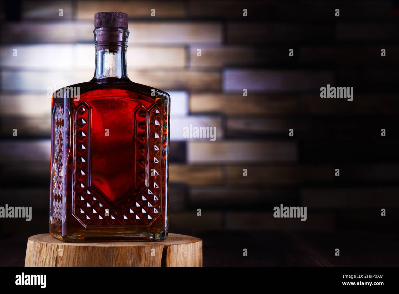 Alcohol bottle on wooden stand by brick wall Stock Photo - Alamy