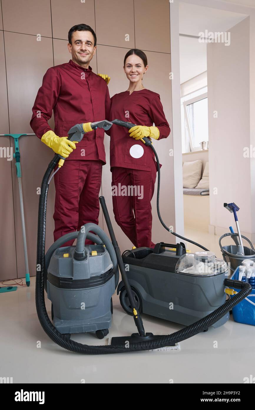 Two workers with cleaning equipment posing for camera Stock Photo - Alamy