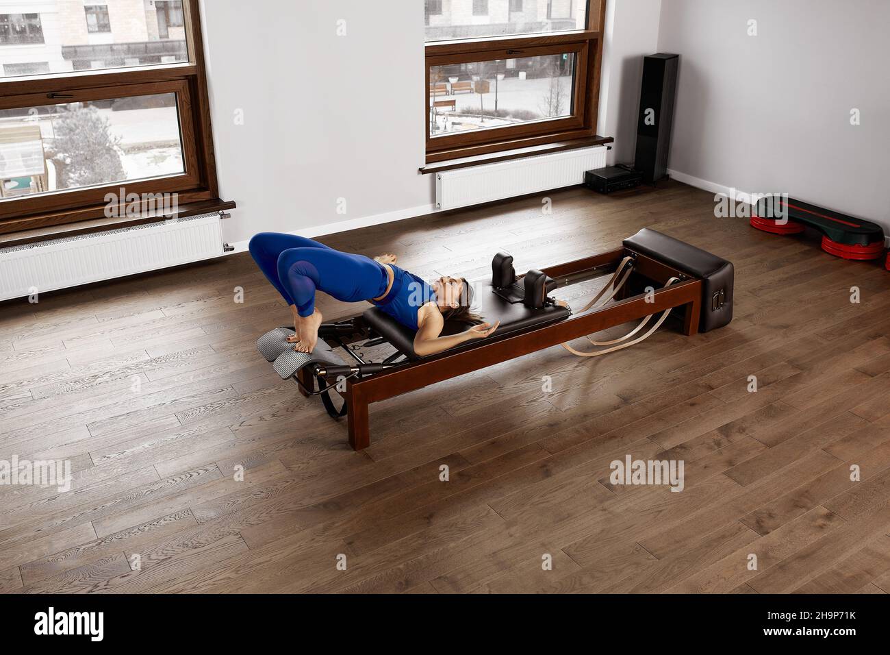 The instructor does exercises on the reformer, a beautiful girl trains ...