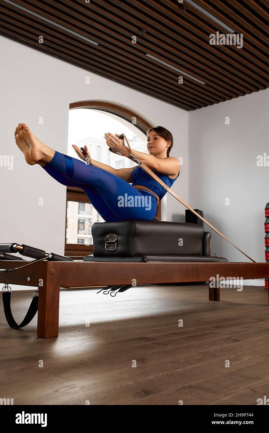 The instructor does exercises on the reformer, a beautiful girl trains ...