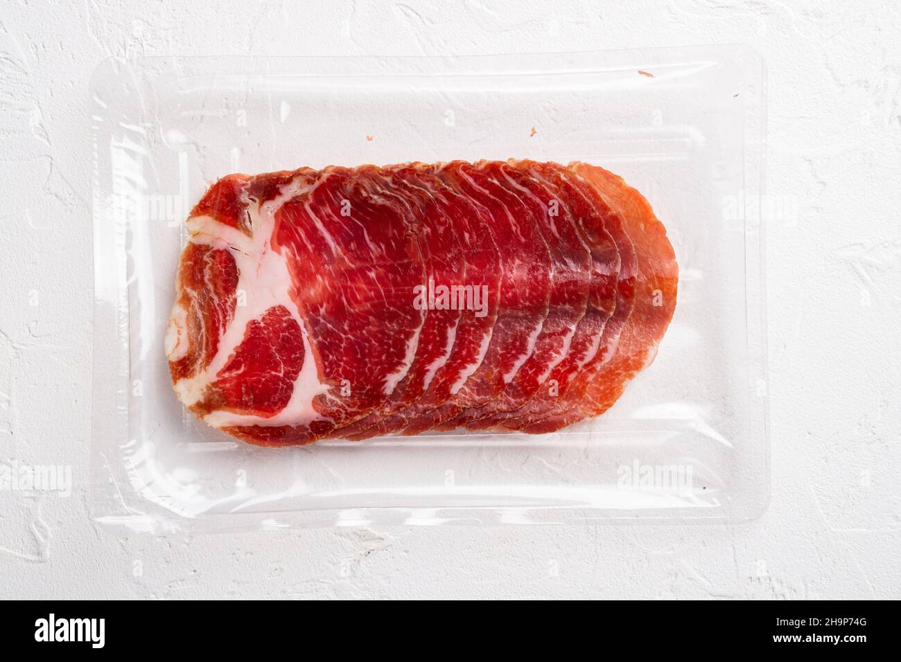 Italian dry cured ham vacuum pack set, on white stone table background ...