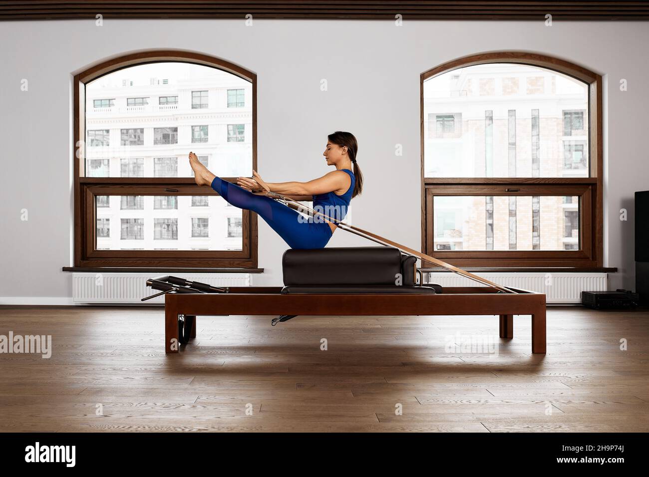 The instructor does exercises on the reformer, a beautiful girl trains ...