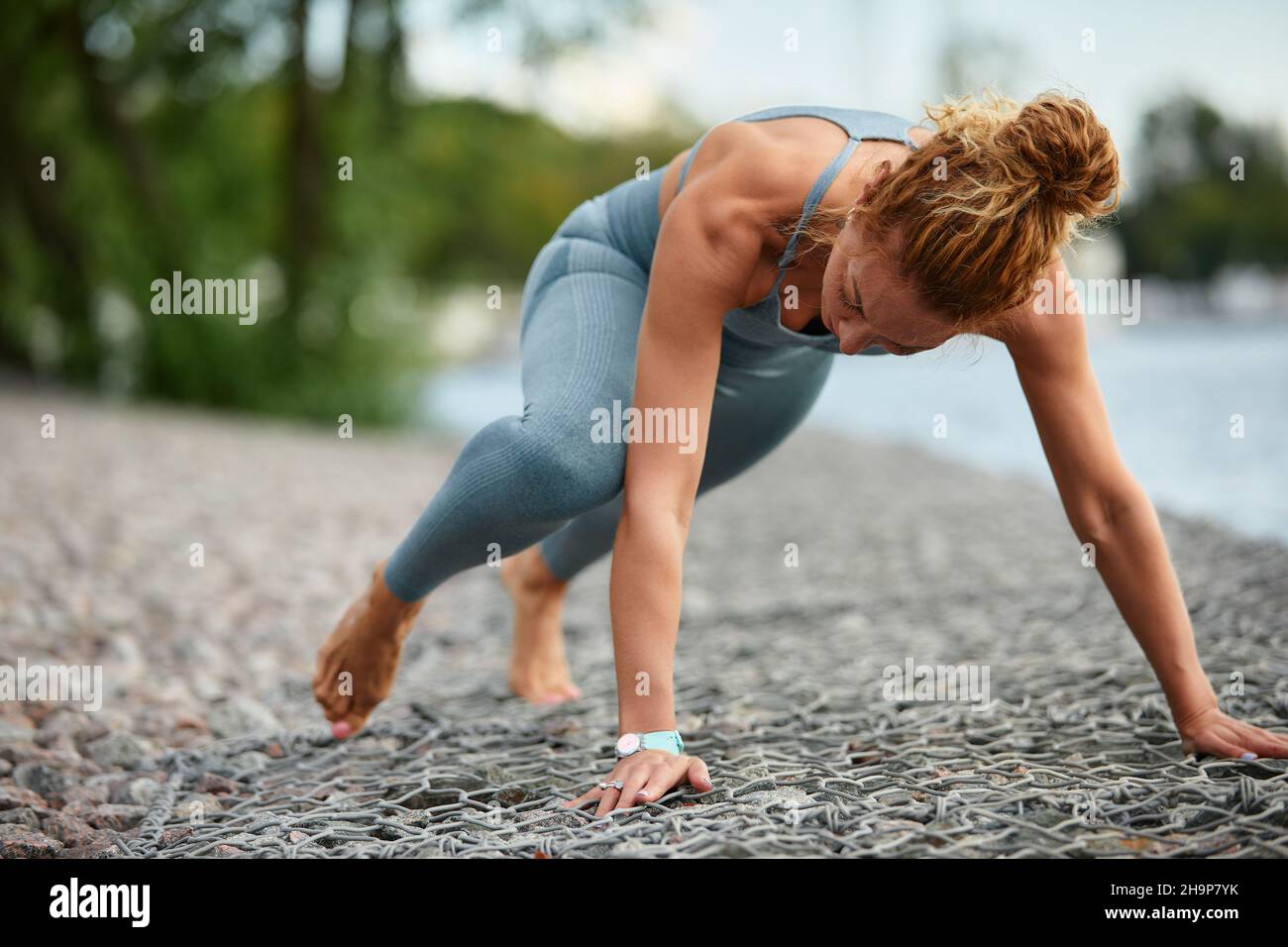 Blonde young athletic woman doing working out in a park in an urban ...