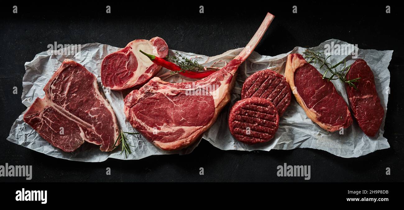 Top view of uncooked tomahawk t bone and sirloin beef steaks garnished ...