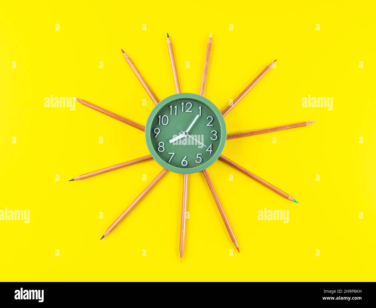 Colorful school crayons in sun shape with alarm clock Stock Photo - Alamy