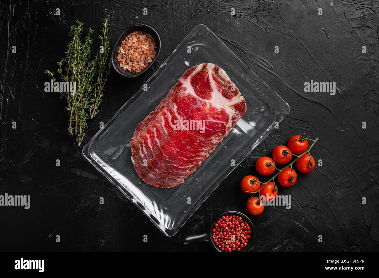 Italian dry cured ham vacuum pack set, on black dark stone table ...