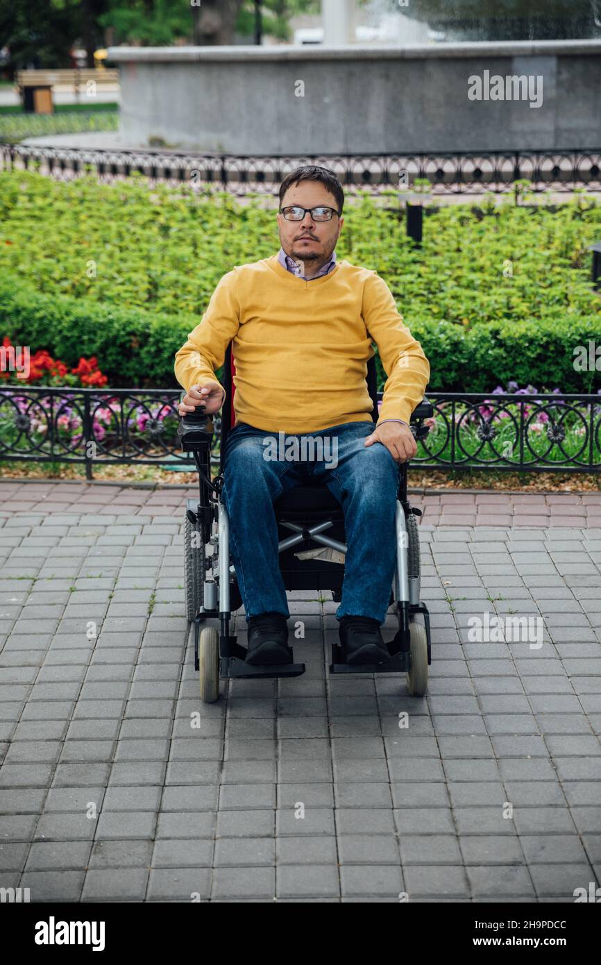 a man with disabilities in a wheelchair walks around the city Stock ...