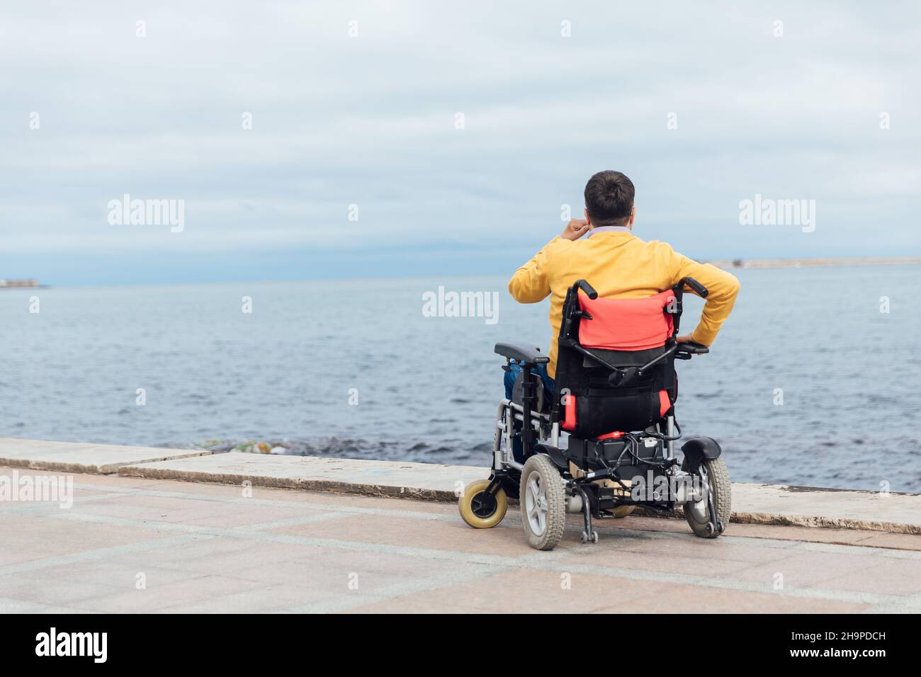 a man with disabilities in a wheelchair walks around the city Stock ...