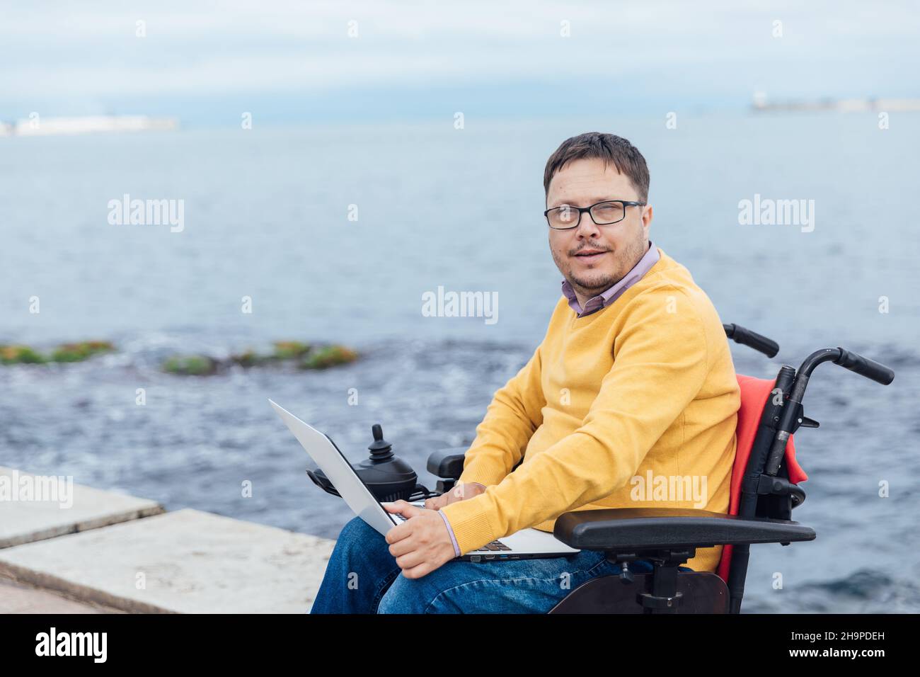 a man with disabilities in a wheelchair works on a laptop Stock Photo ...
