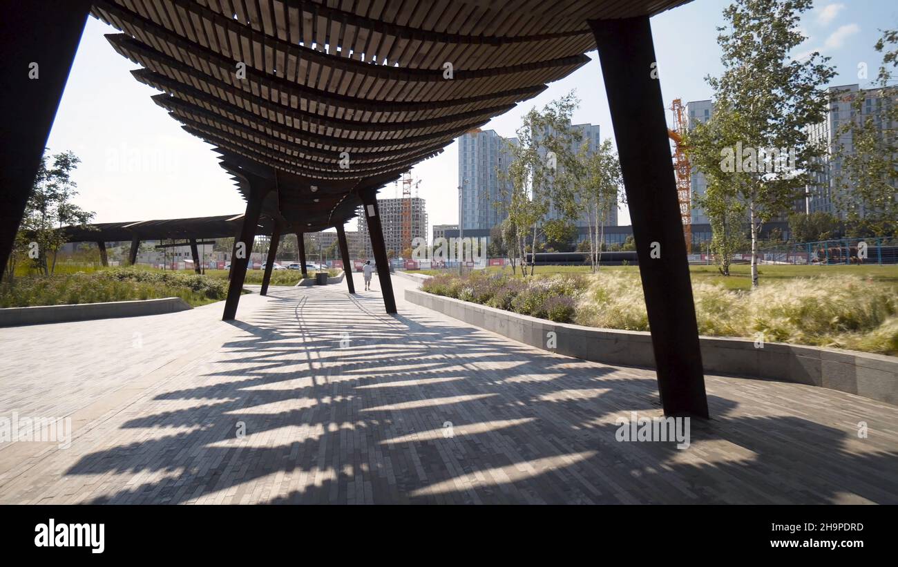 Modern pergolas in park on sunny day. Action. Long pavilions or ...