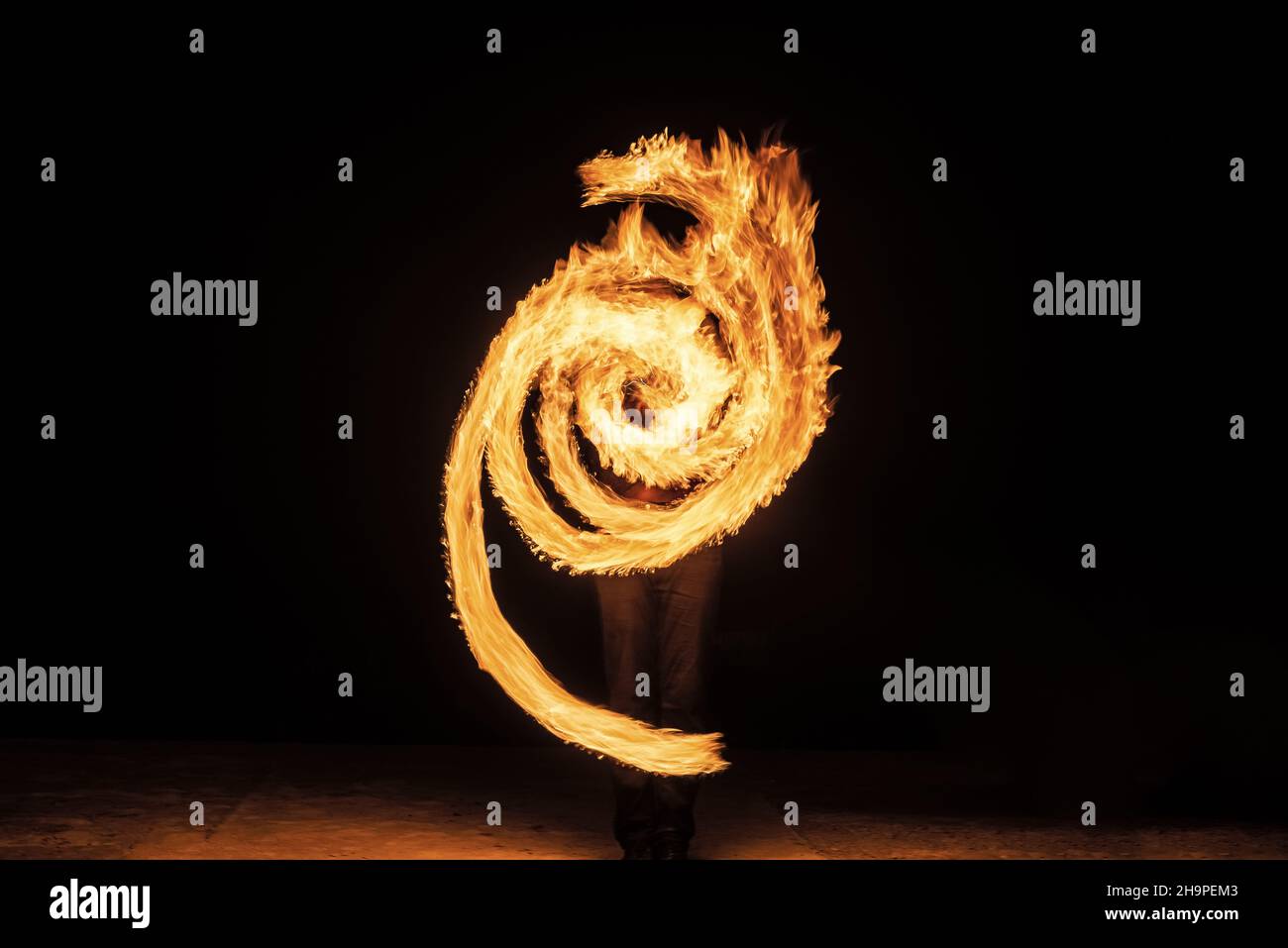 Fire artist perform fiery circular arcs pattern at night in dark ...