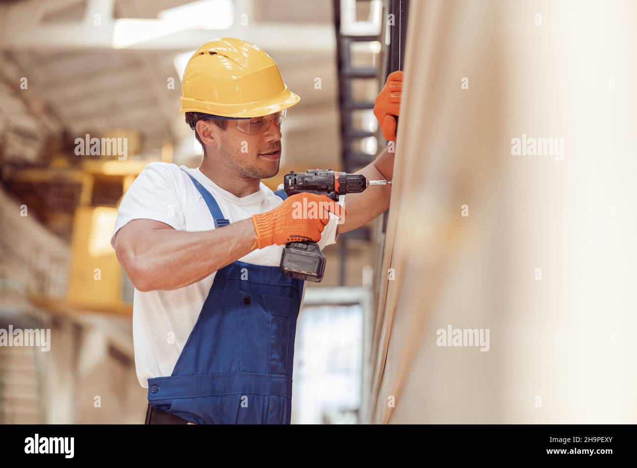 Male worker using cordless electric drill at construction site Stock ...