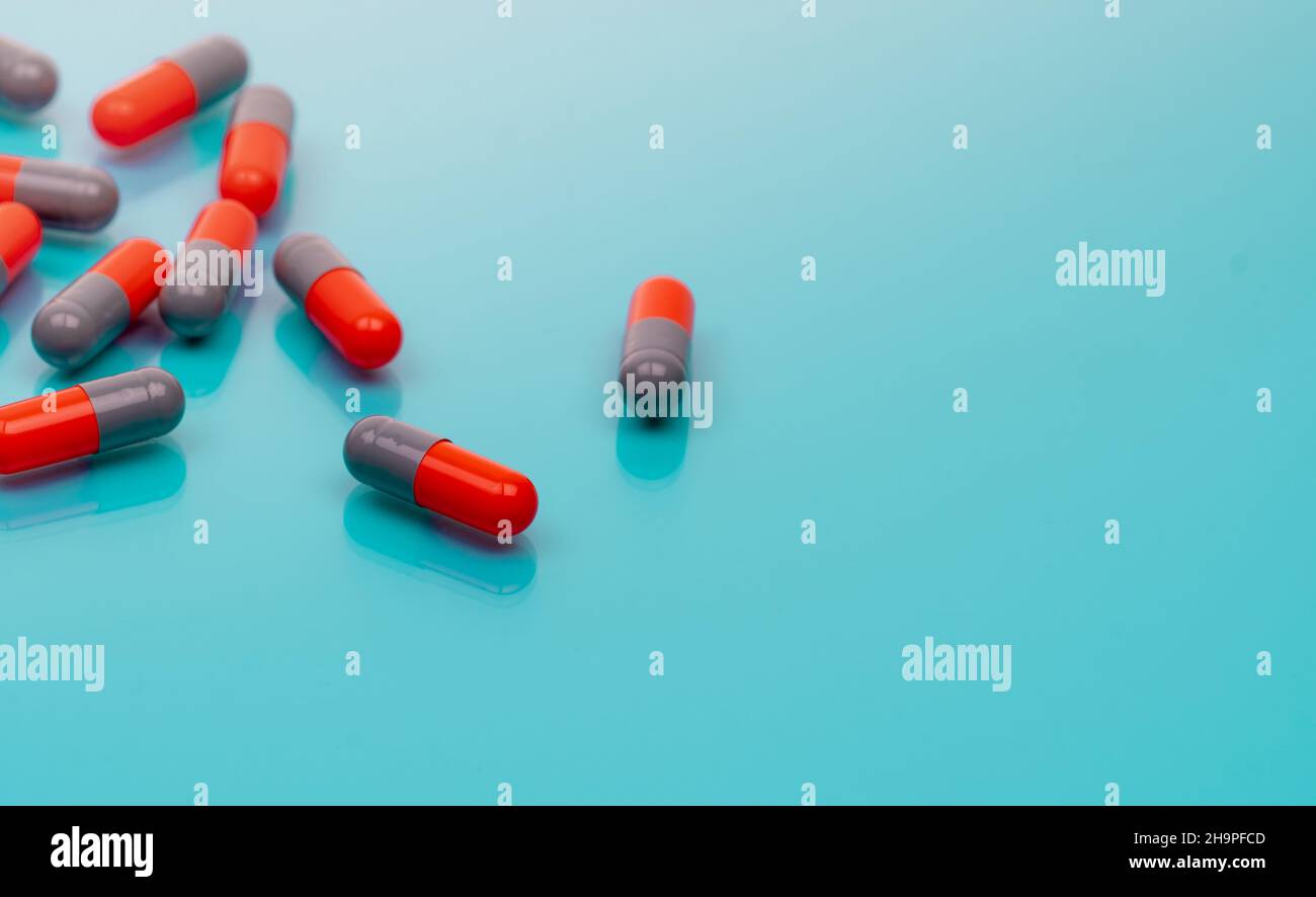 Orange and gray capsule pills on blue background. Pharmaceutical ...