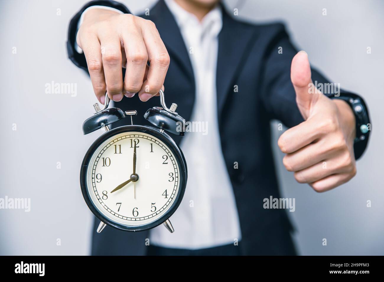 Business people thumbs up with alarm clock for punctual good time or ...