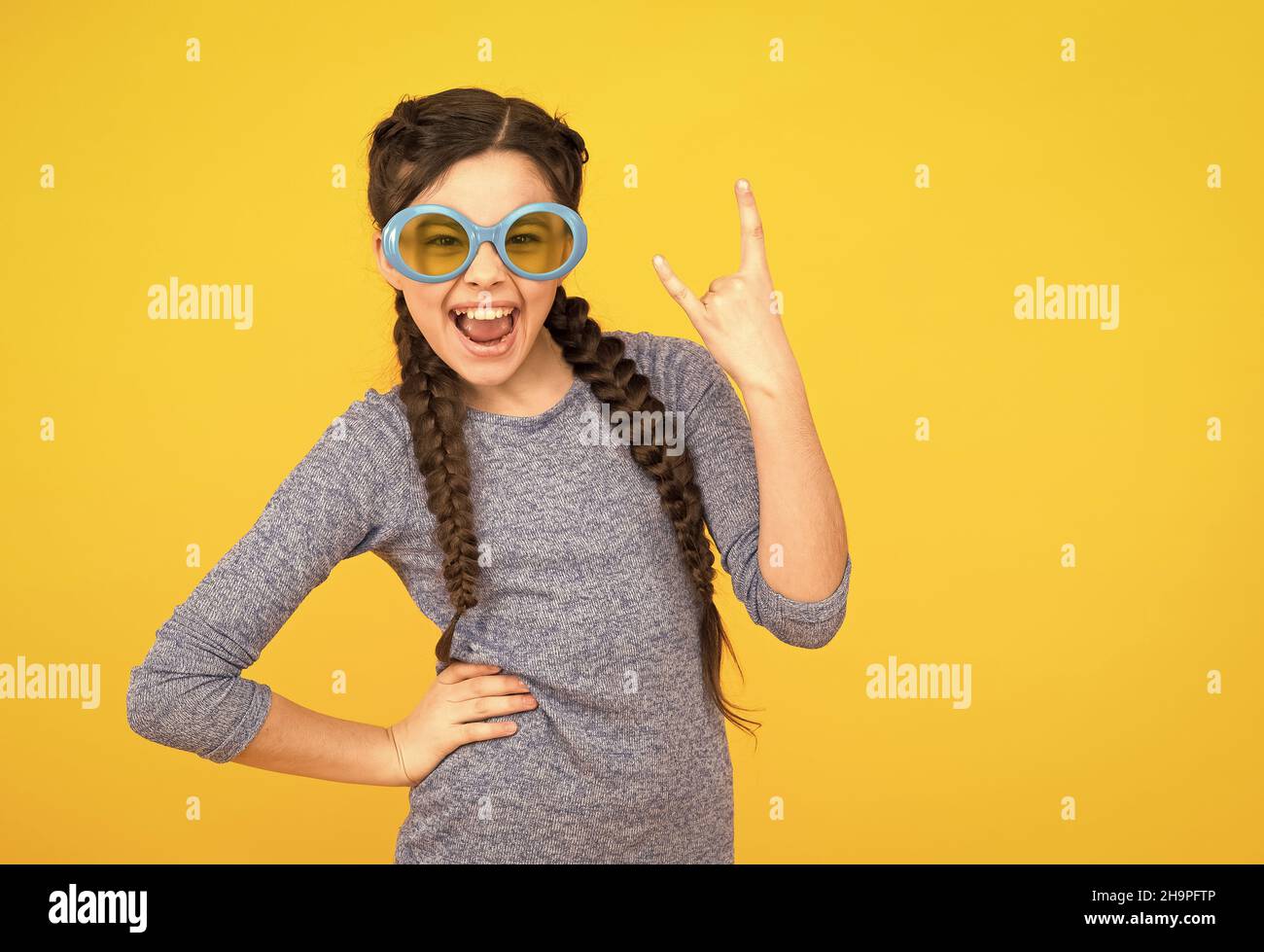 happy child girl has fashionable hairstyle in glasses on yellow background, ready for vacation ...