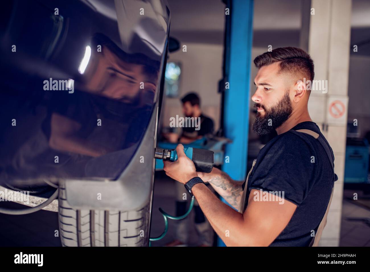 Car service worker changing wheel of a sport car in his workshop Stock ...